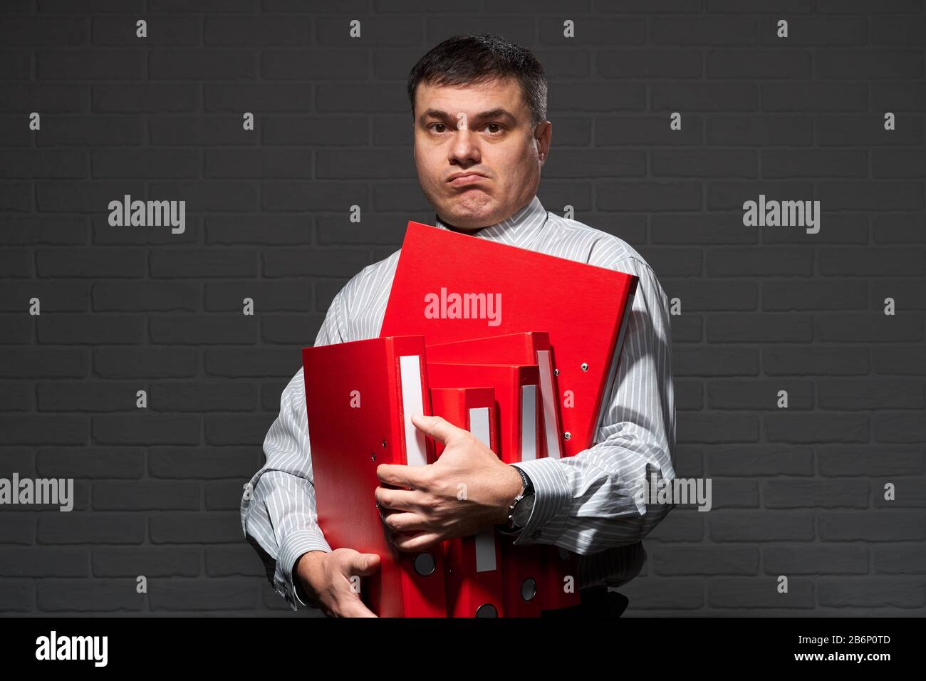 Very busy businessman closeup portrait, posing with red folders ...