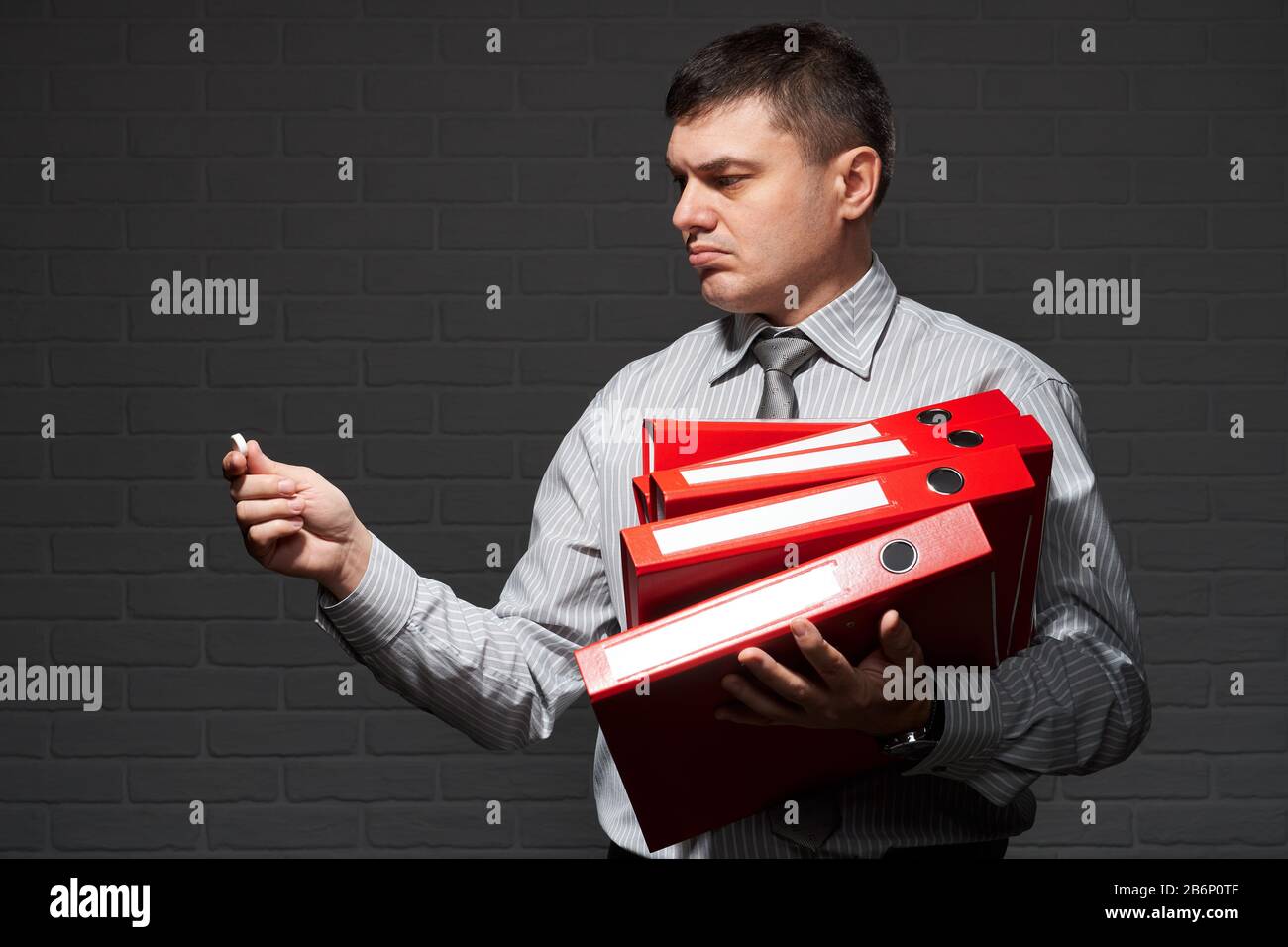 Very busy businessman closeup portrait, posing with red folders ...