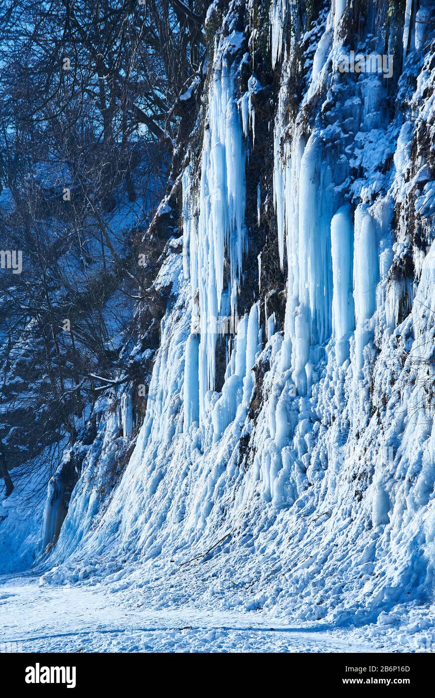 Large icicles hang from river bank cliff Stock Photo - Alamy