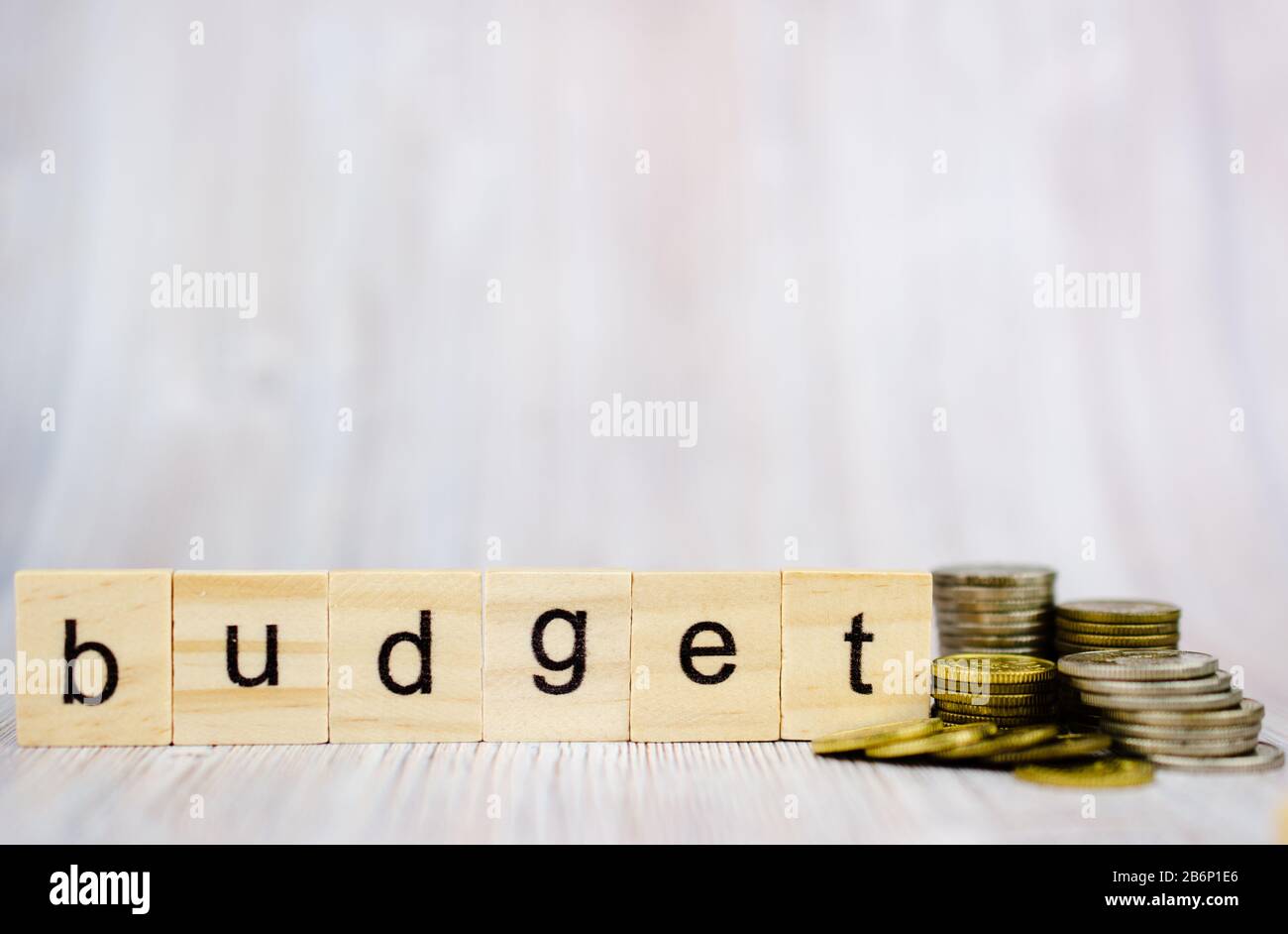 Wooden cube block with word budget and coins on the stack and scattered ...