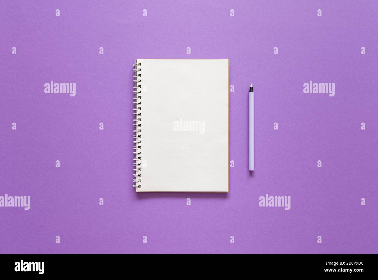 Open spiral notepad on a purple background , notebook and pen lie on ...