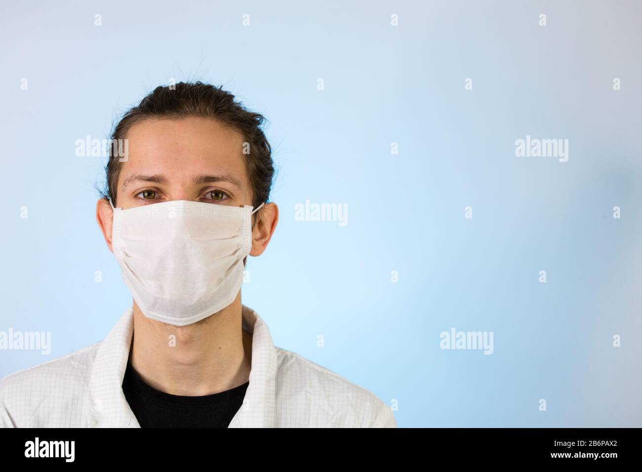 An adult male dressed in a white lab coat with a protective face mask ...