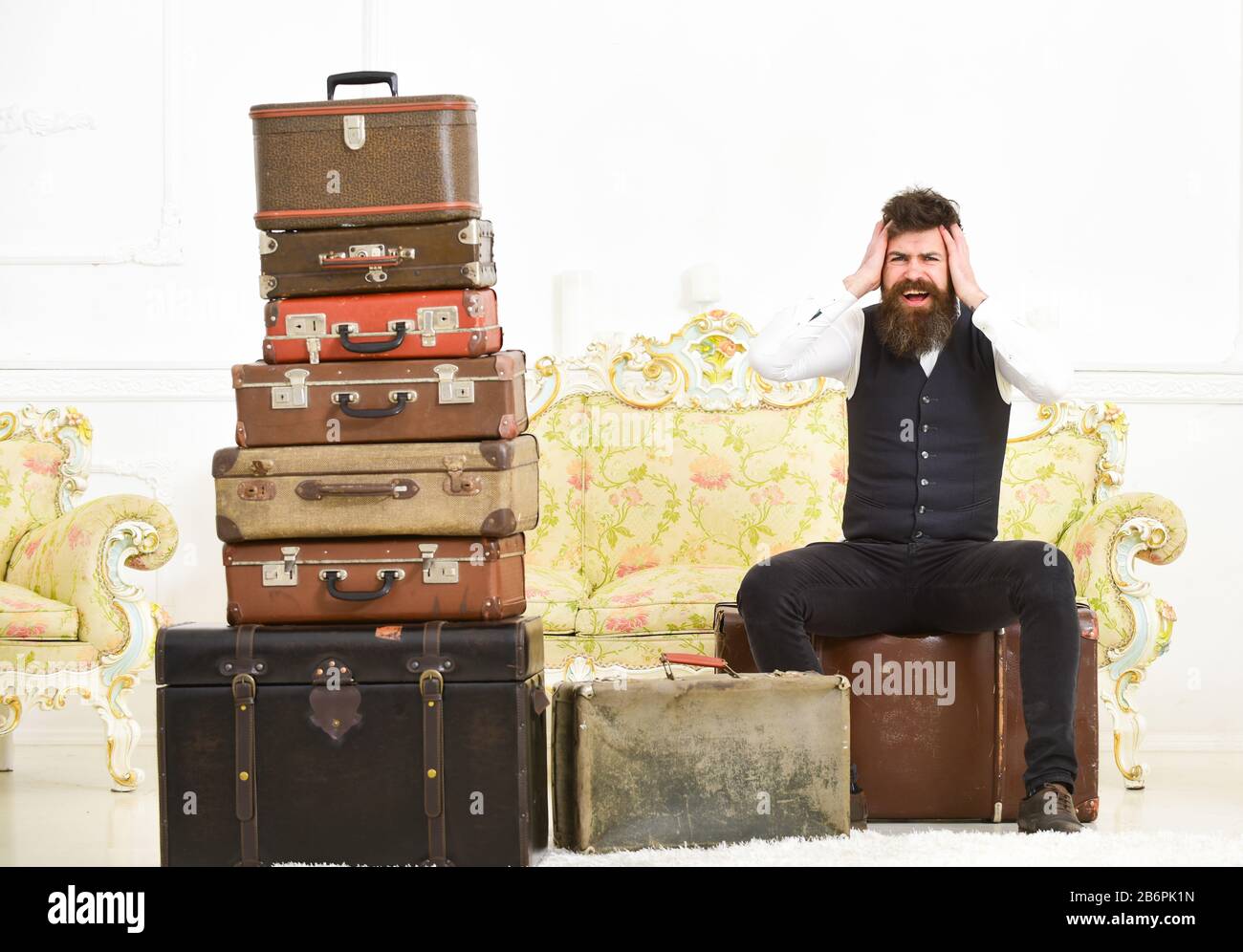 Man, butler with beard and mustache delivers luggage, luxury white ...