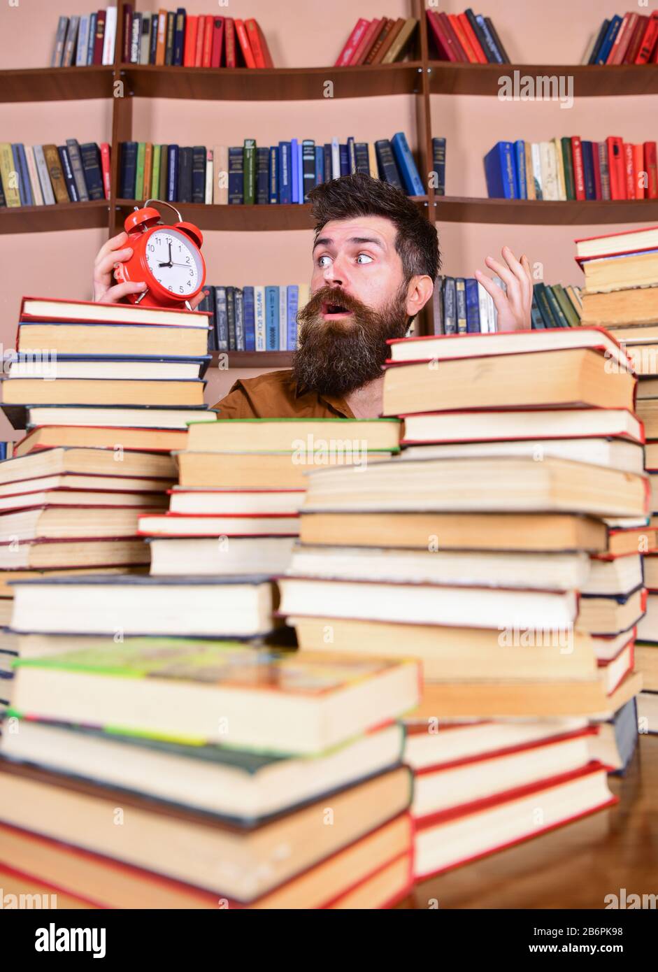 Man, scientist peeking out of piles of books with alarm clock. Teacher ...
