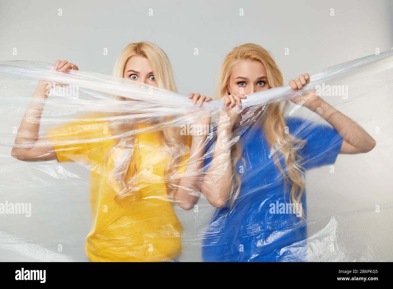 Young women volunteers in yellow and blue t-shirts behing a wall of non ...