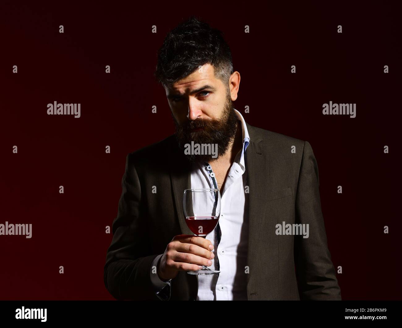 Man in suit toasting with sparkling glass of red wine. Connoisseur with ...