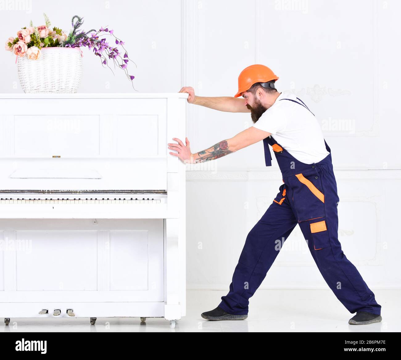 Side view bearded man trying to move heavy old piano isolated on white ...
