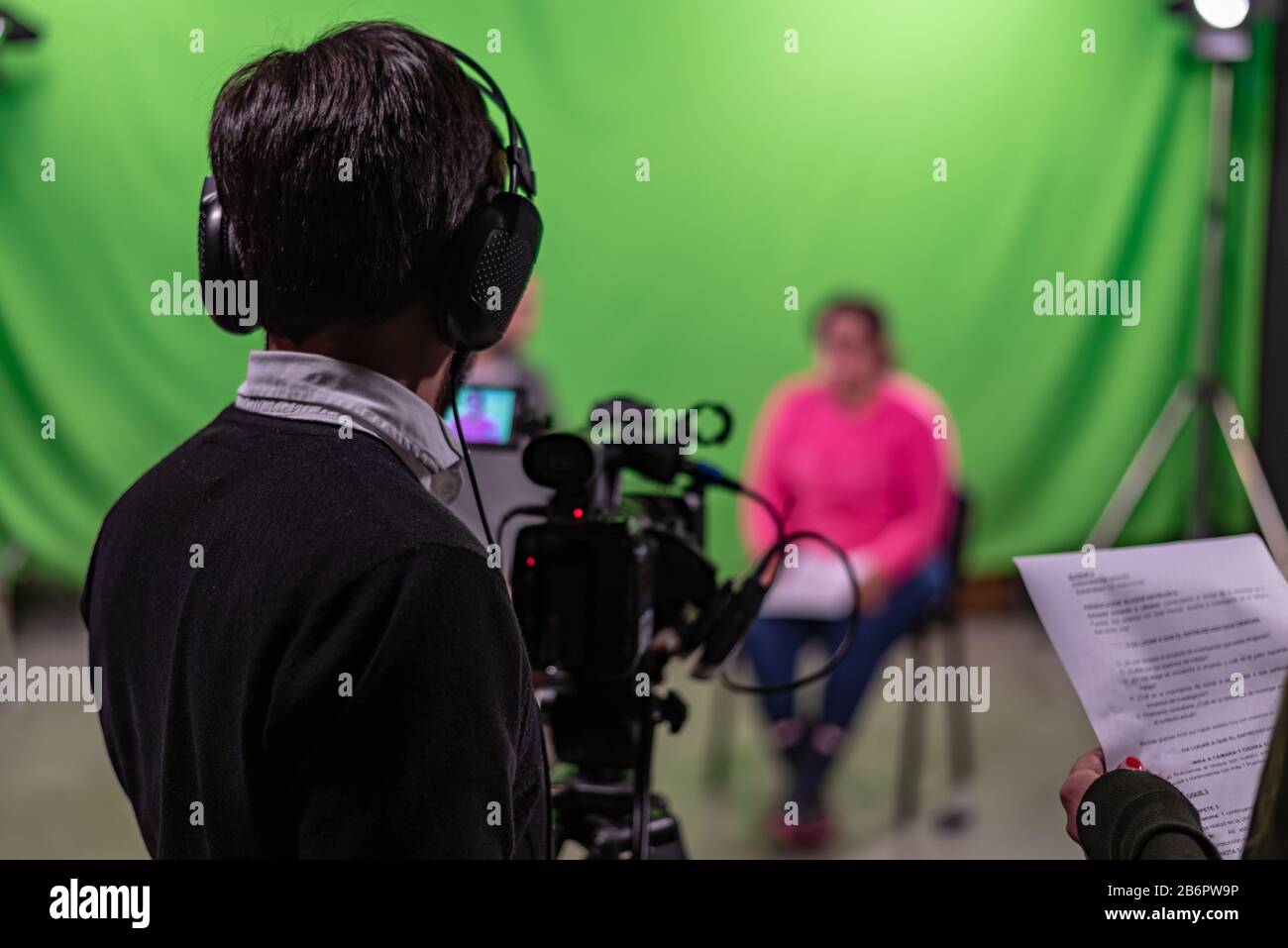 Journalist talking to camera, cameraman recording in a chroma and ...