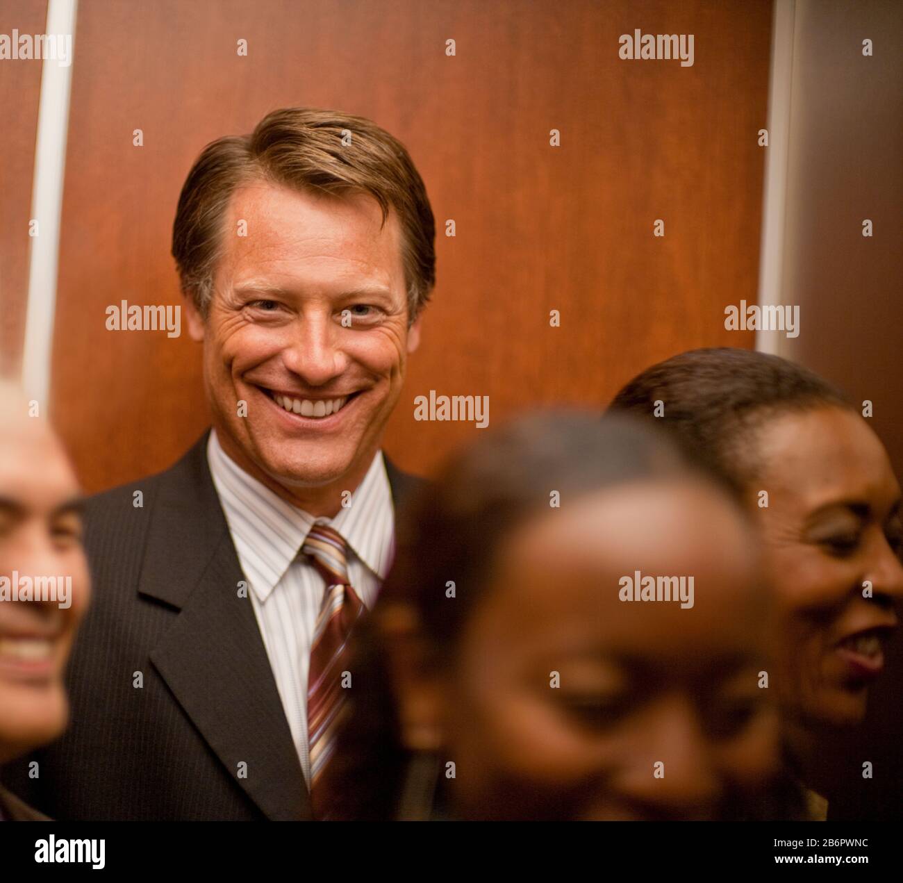 Businessman smiling in a crowded elevator Stock Photo - Alamy