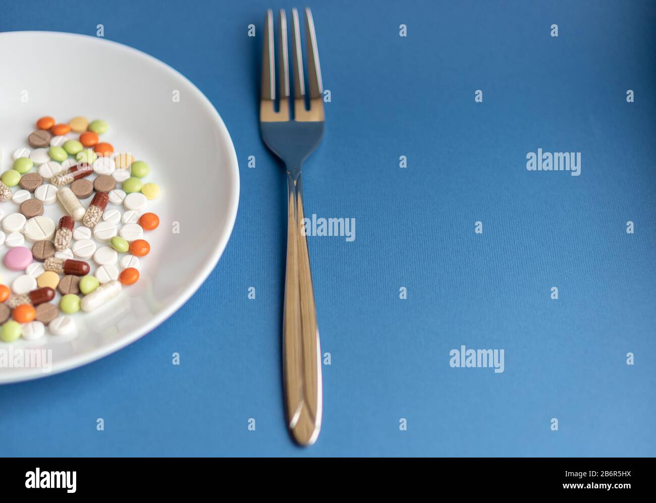 Pills on a white plate. Gestures with a fork on a plate with pills ...