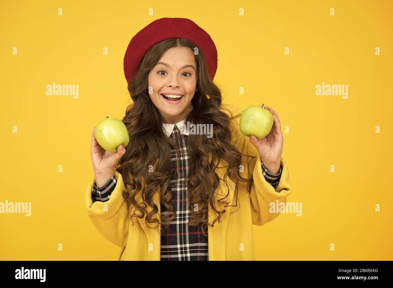 Back to school snack. Happy child hold natural apples yellow background ...