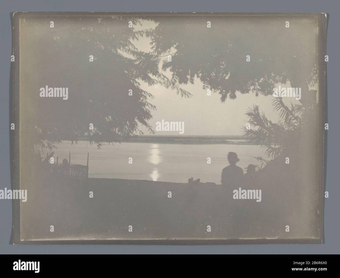 View of a river from an overgrown bank with two figures in silhouette ...
