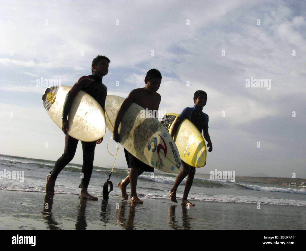 Huanchaco, Pero. Three Peruvian surfer boys coming out of the sea with ...