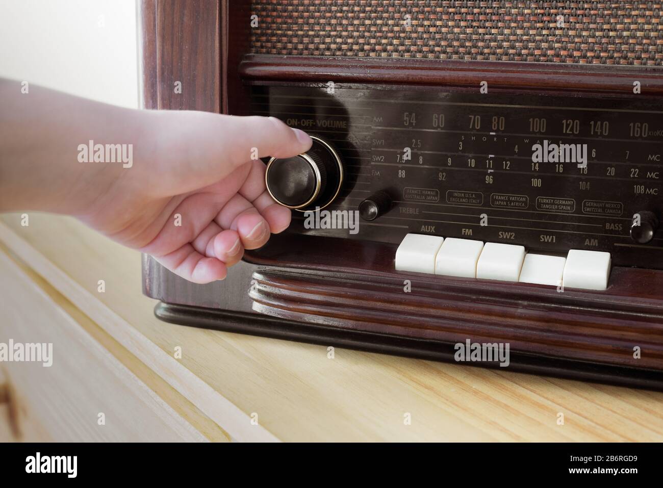 A woman hand adjusting the button vintage radio volume for listen music ...