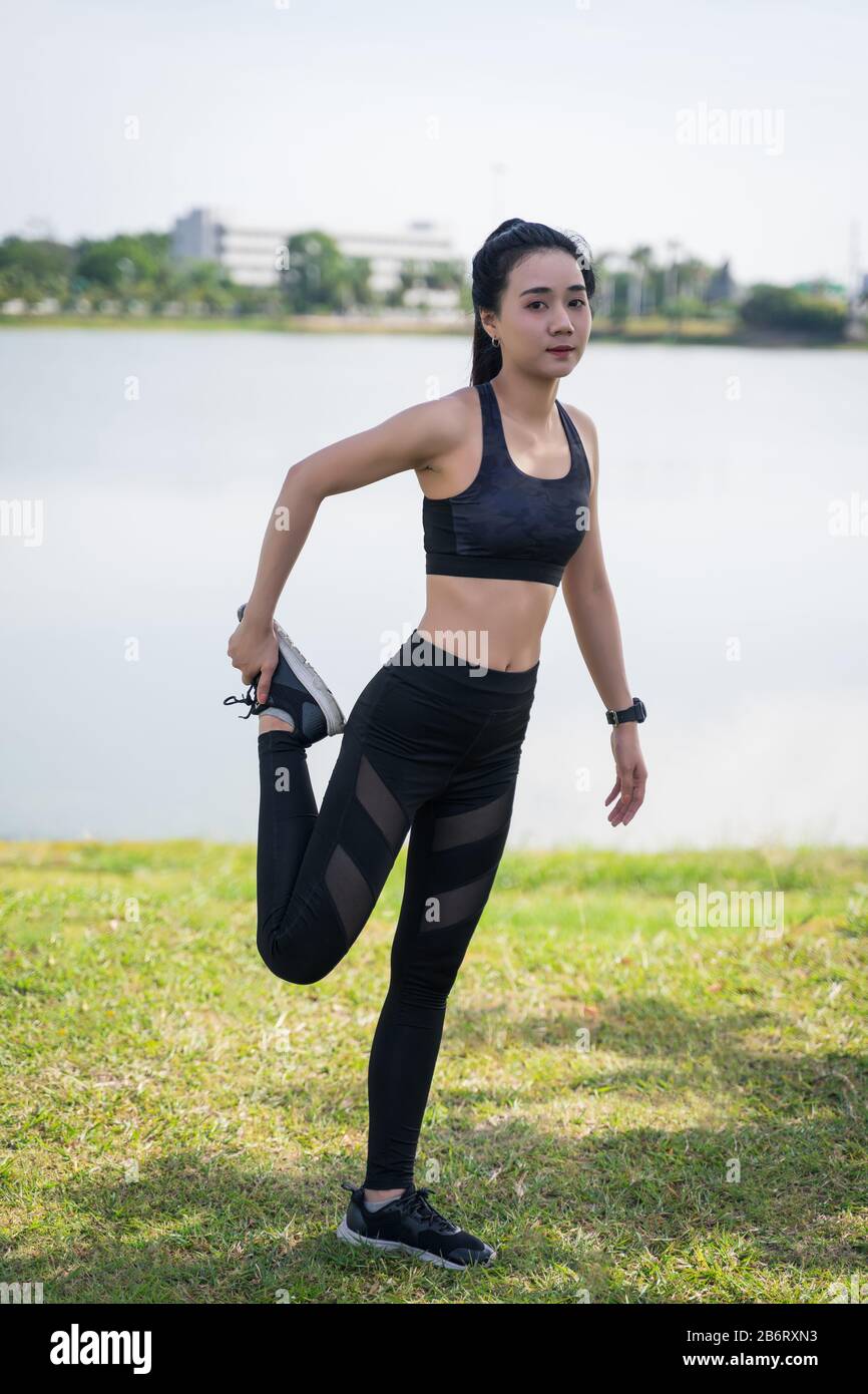 A young Asian woman stretching before and after fitness workout besides ...
