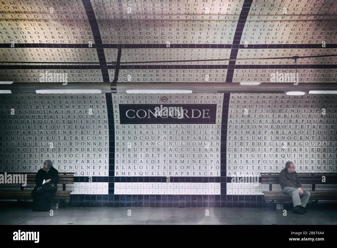 Two people facing opposite directions under a sign reading Concorde ...