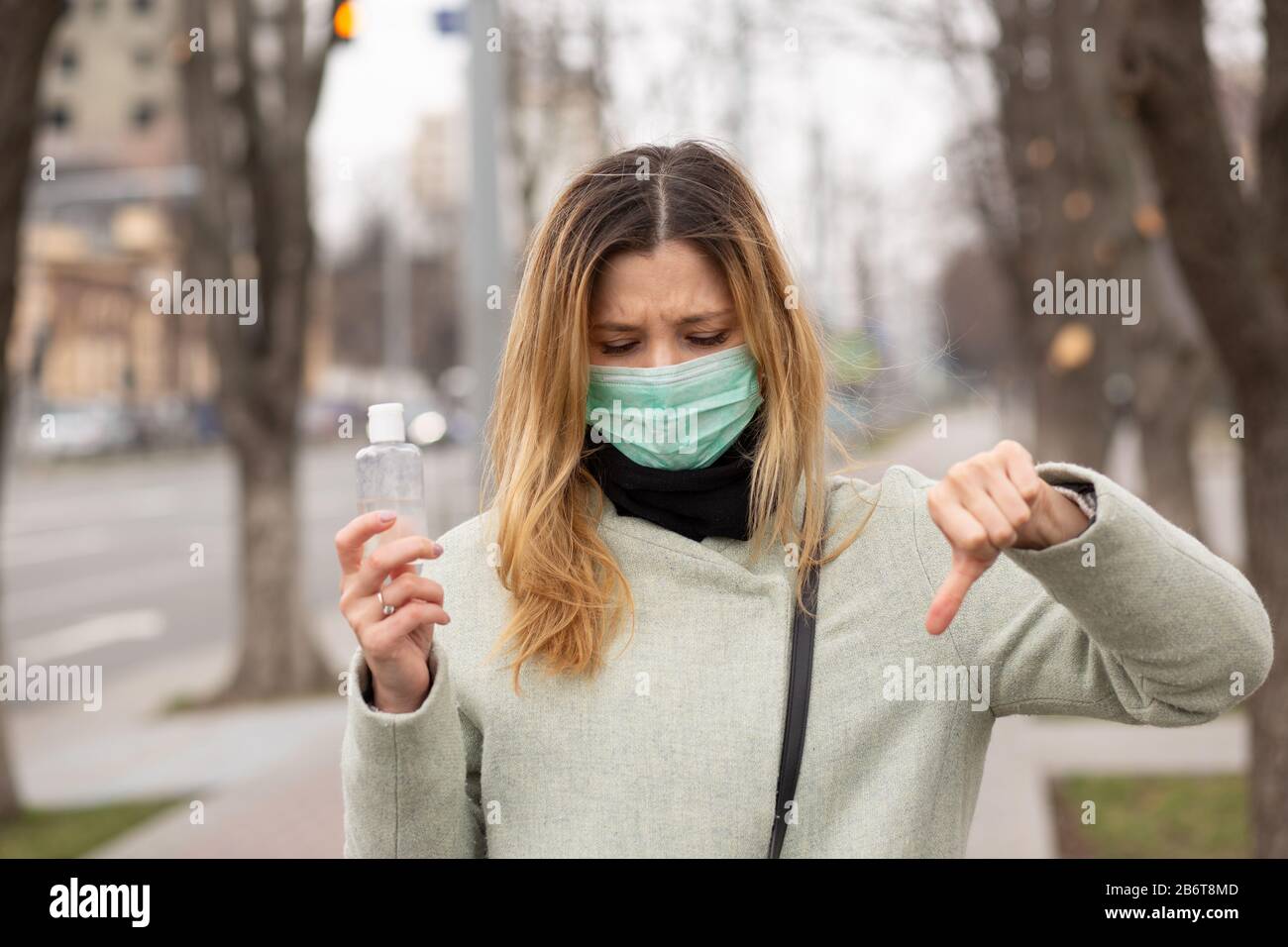 Sick unhappy girl, a blonde young woman wearing surgery medical mask ...