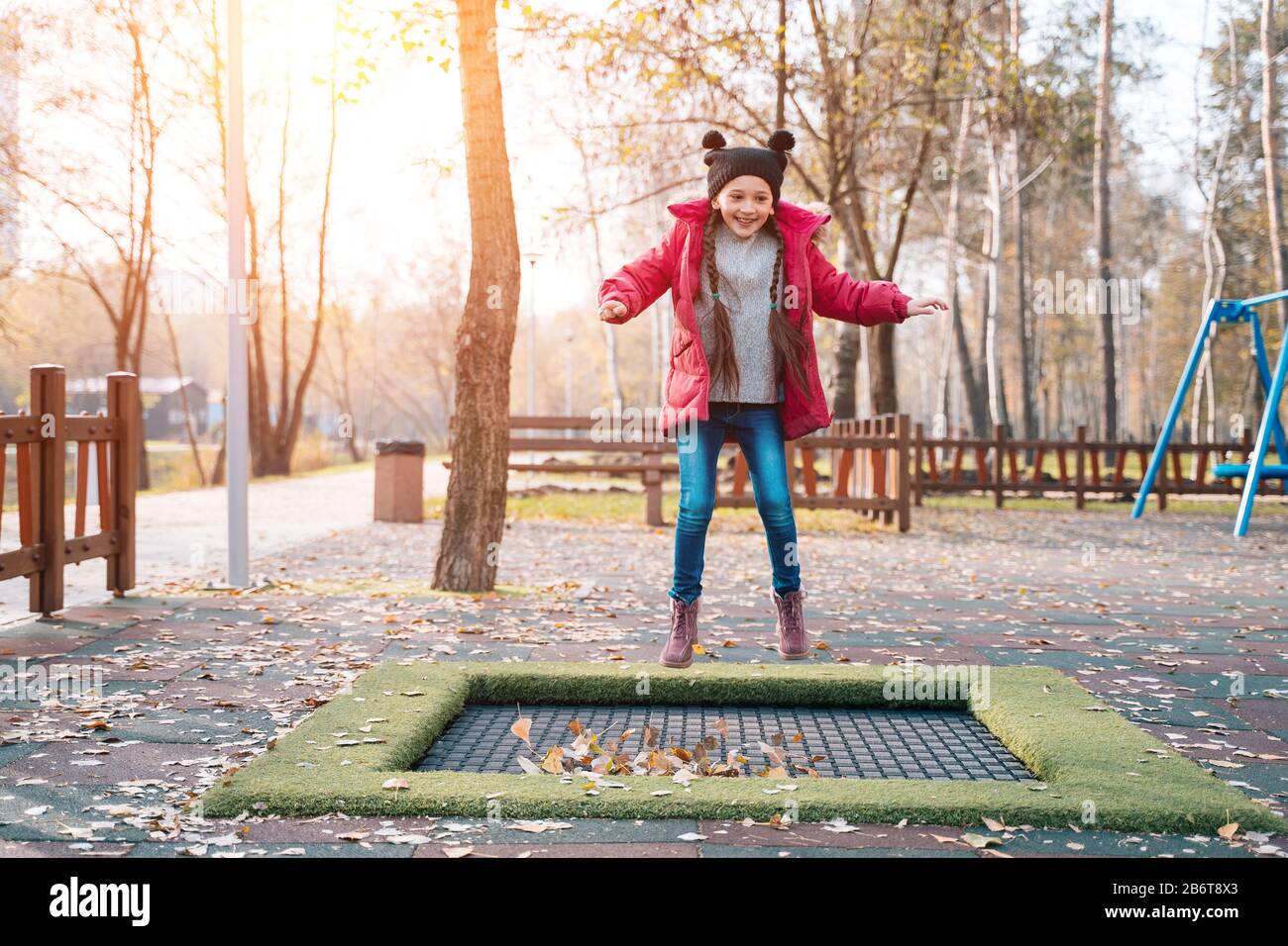 Happy school girl jumping on a small trampoline in the park Stock Photo ...