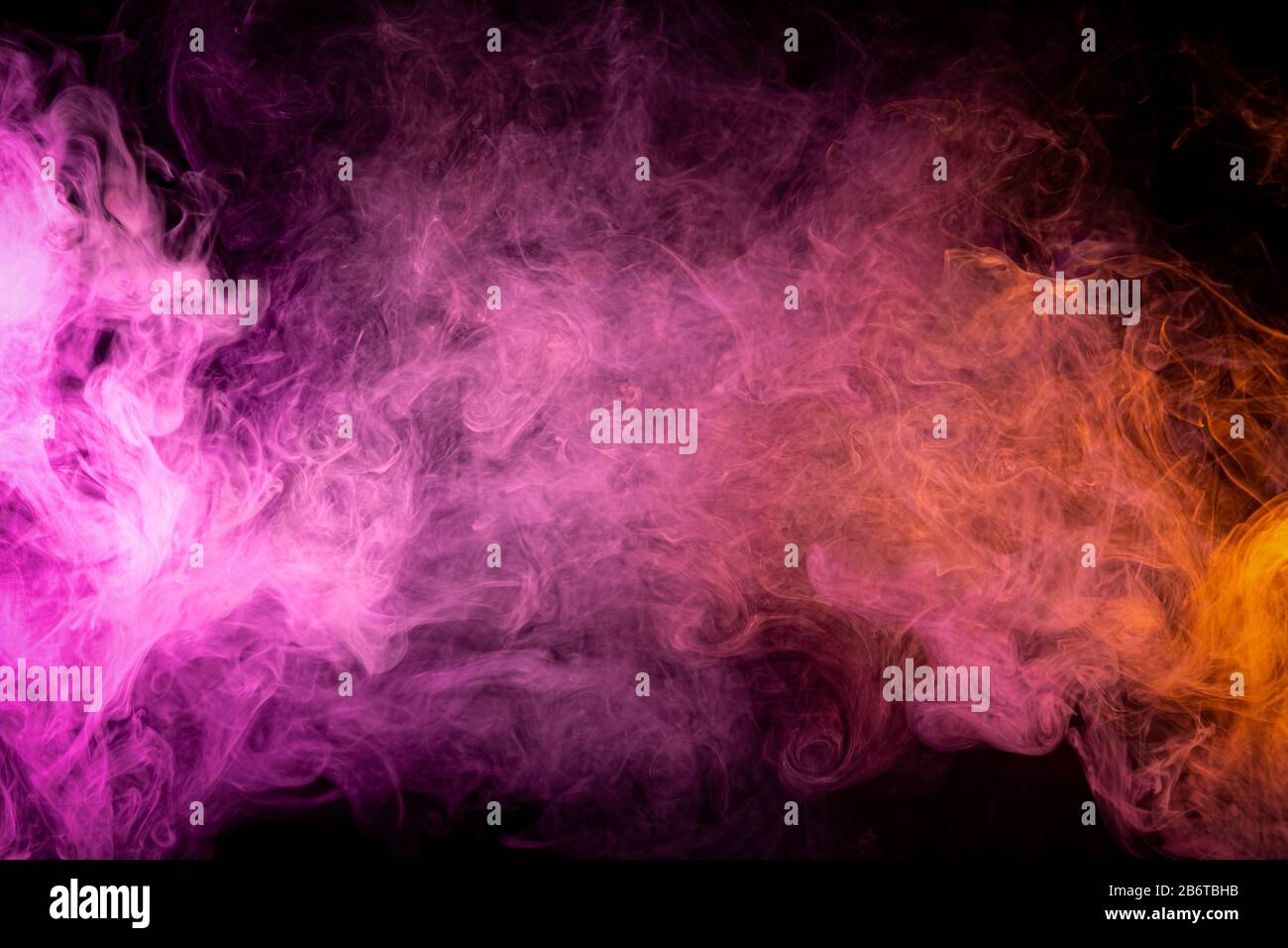 Thick colorful smoke of red and pink on a black isolated background ...