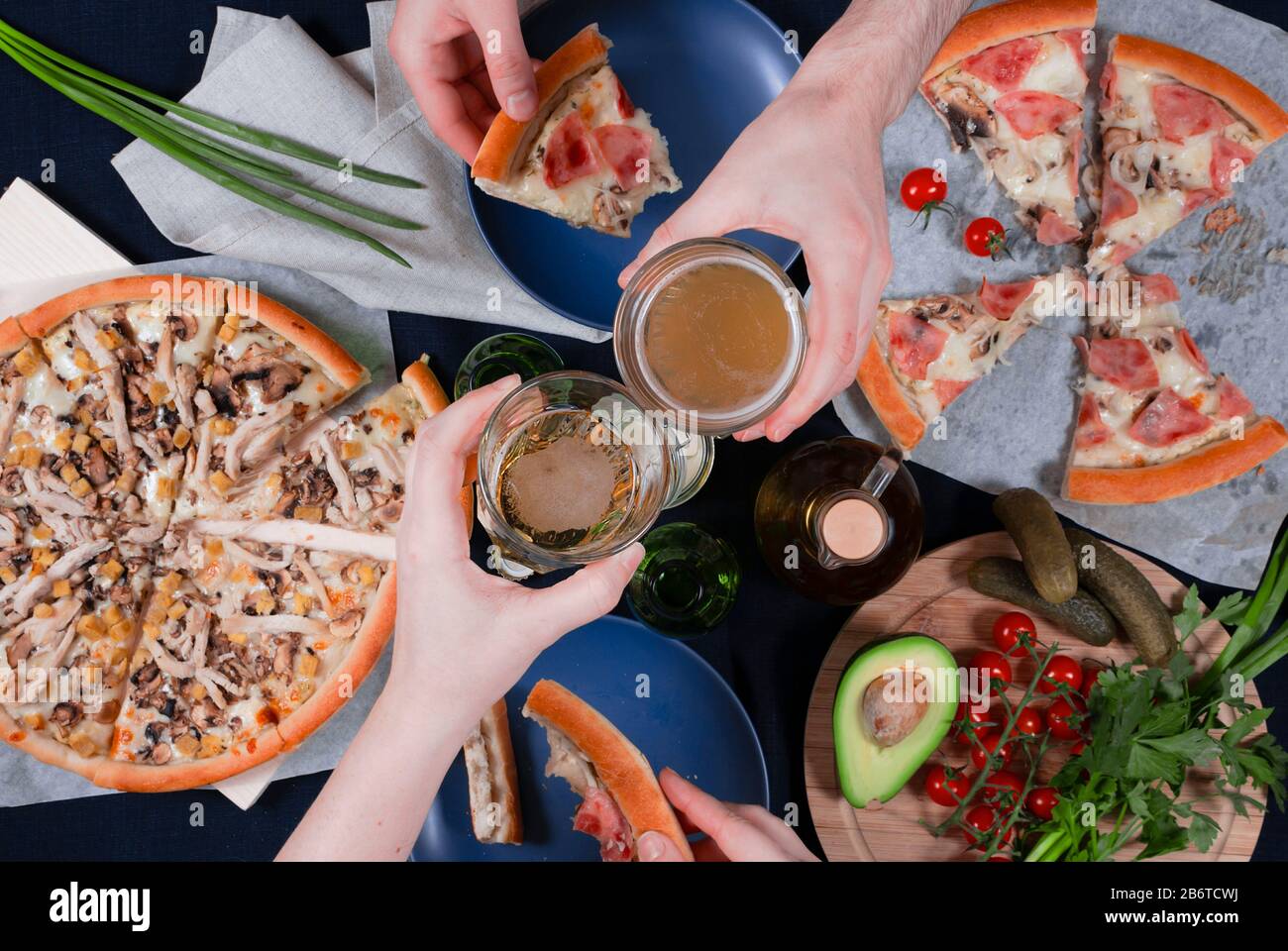 Friends clink glasses with beer over the table served full of delicious ...
