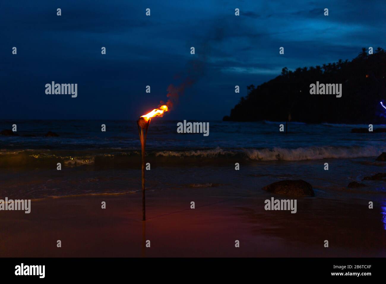 Burning torch on the sandy beach of the ocean Stock Photo - Alamy