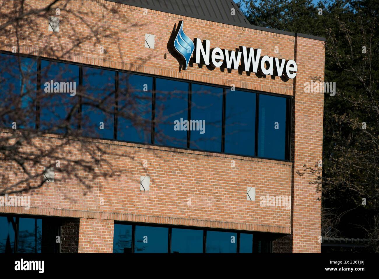 A logo sign outside of a facility occupied by NewWave Telecom ...