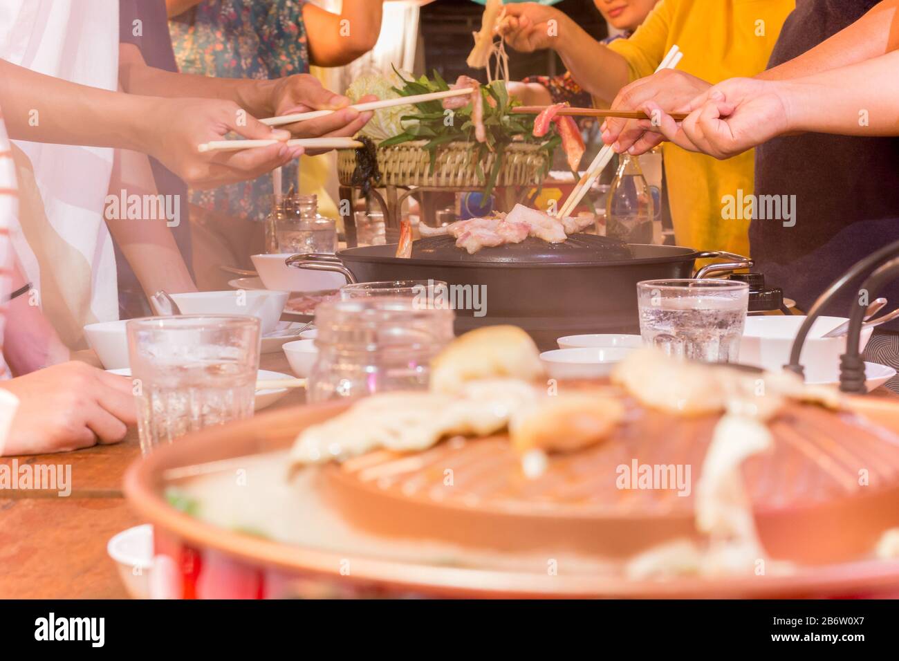 Family dinner hand with chopstick cooking praw on hot BBQ pan Stock ...