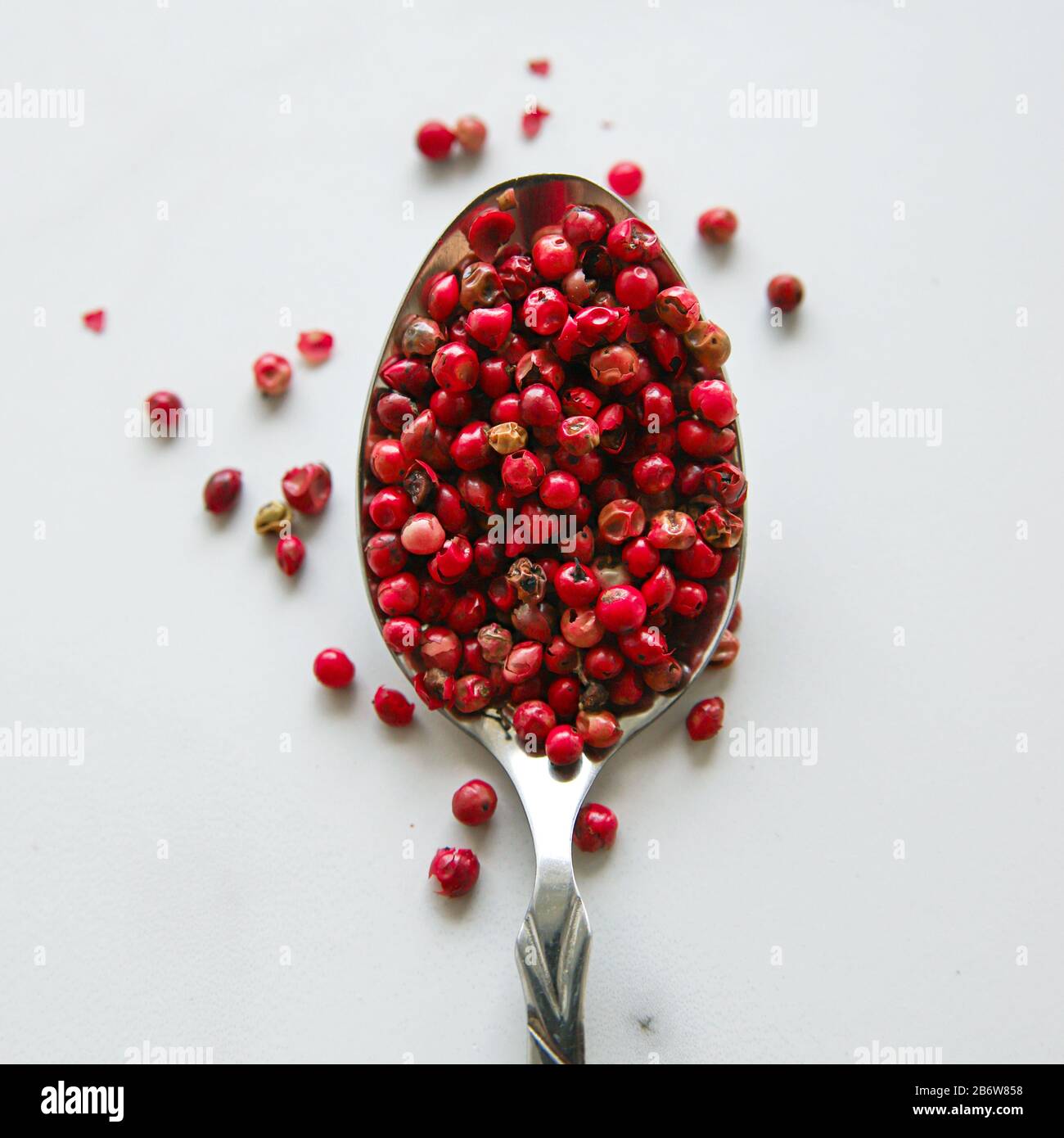 Pink pepper is spoon on marble background. Close up and top view spice ...