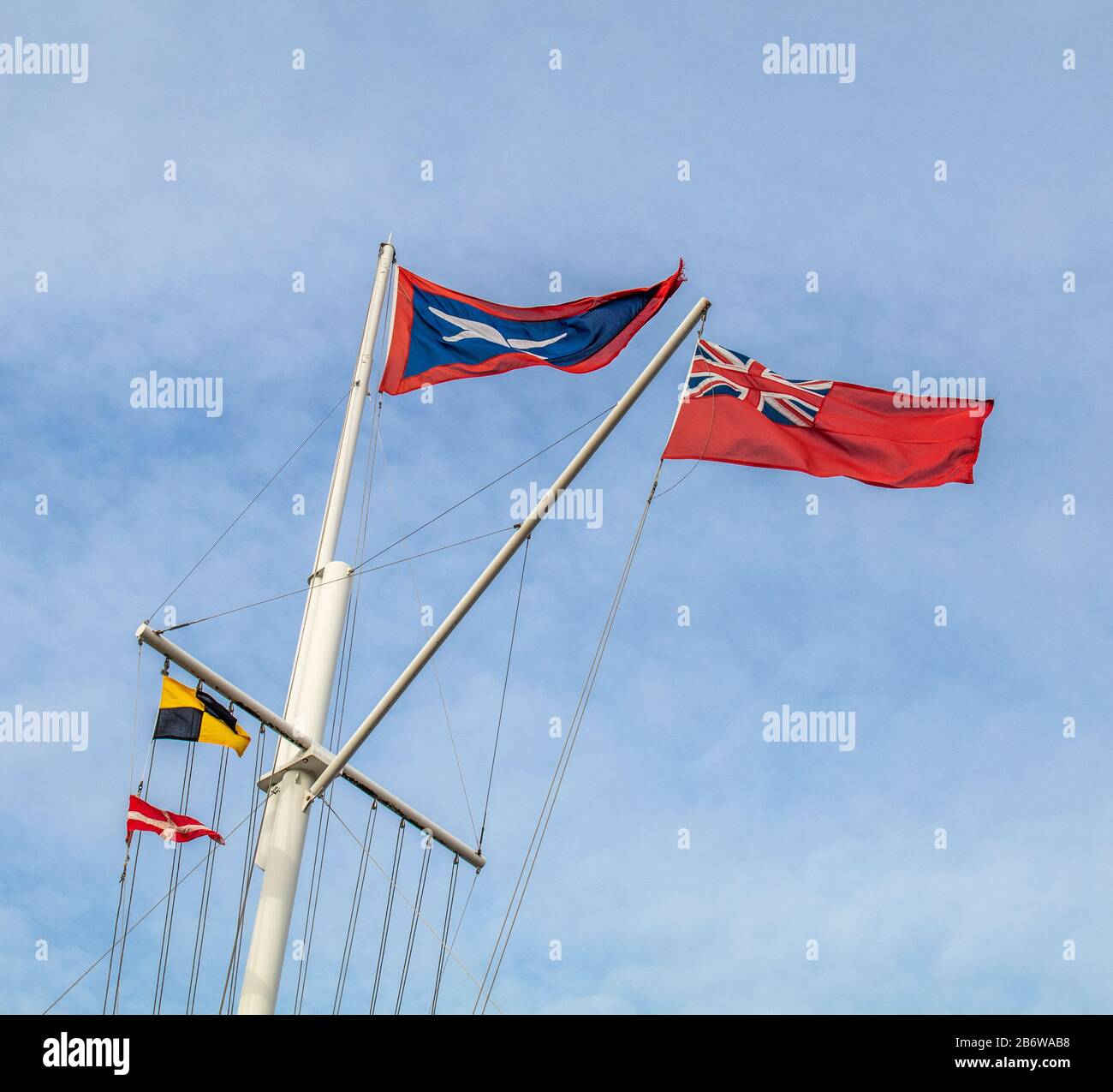 flags flying in the wind on a mast at yacht club including the English ...