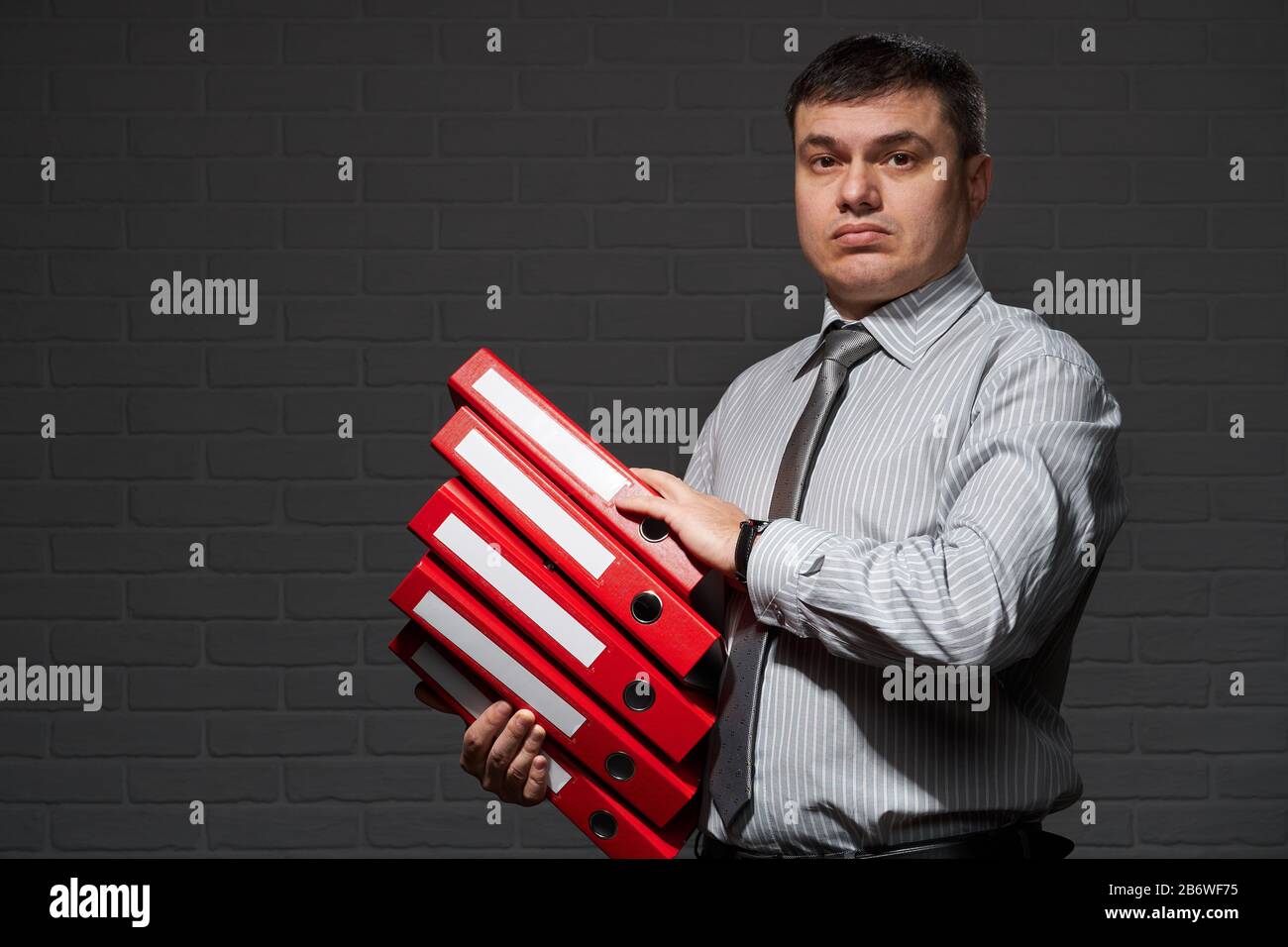 Very busy businessman closeup portrait, posing with red folders ...