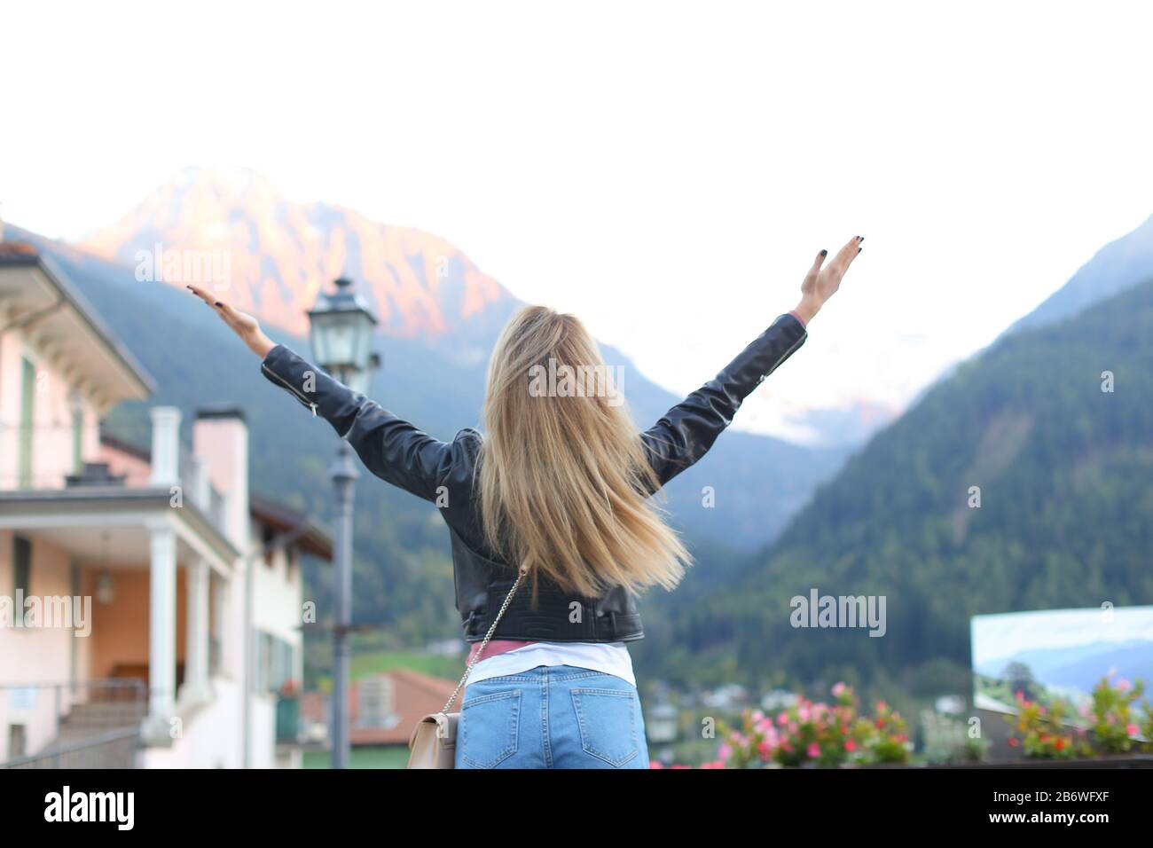 Back view of girl standing with raised hands in mountain village Stock ...