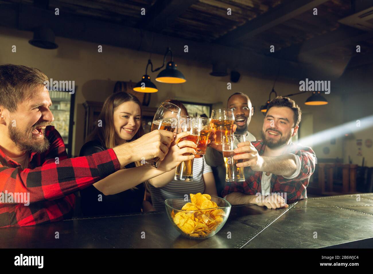 Sport fans cheering at bar, pub. Clinking beer glasses while watching ...