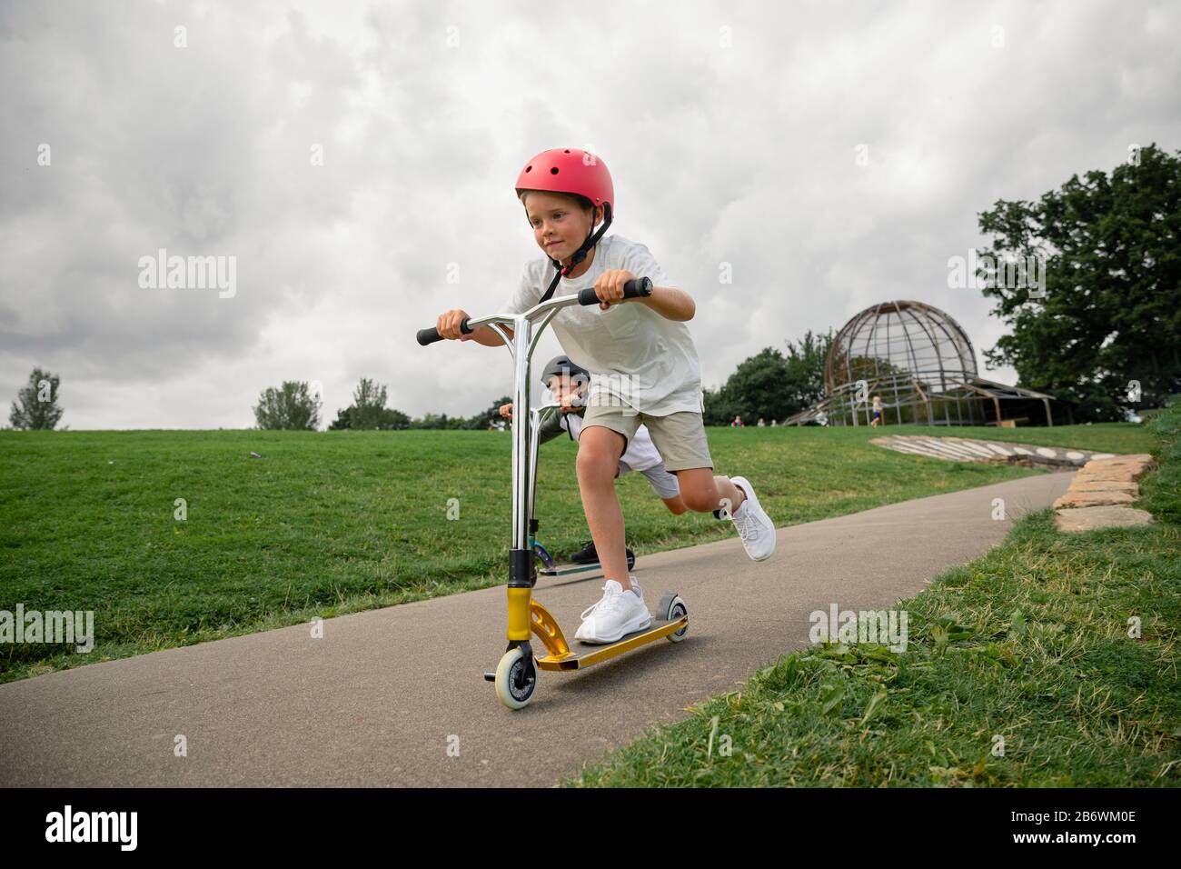 A side view shot of two young boys playing together on push scooters ...