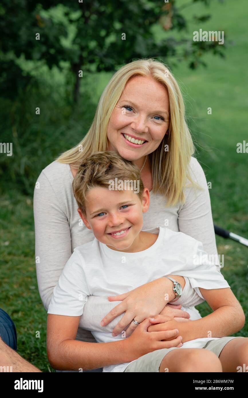 A front-view shot of a mother and son sitting down on the grass ...