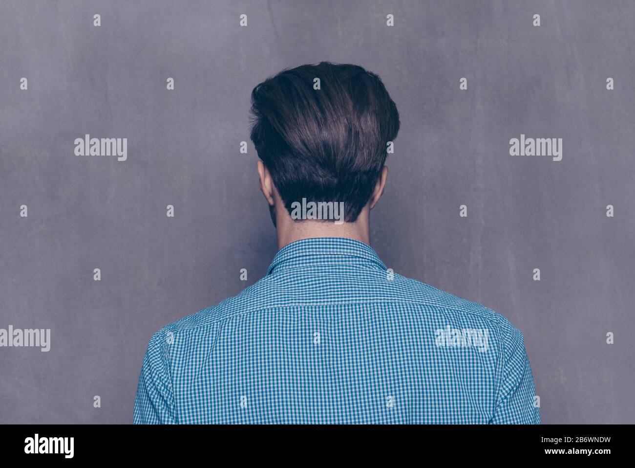 Back view of young guy in blue shirt on gray background Stock Photo - Alamy