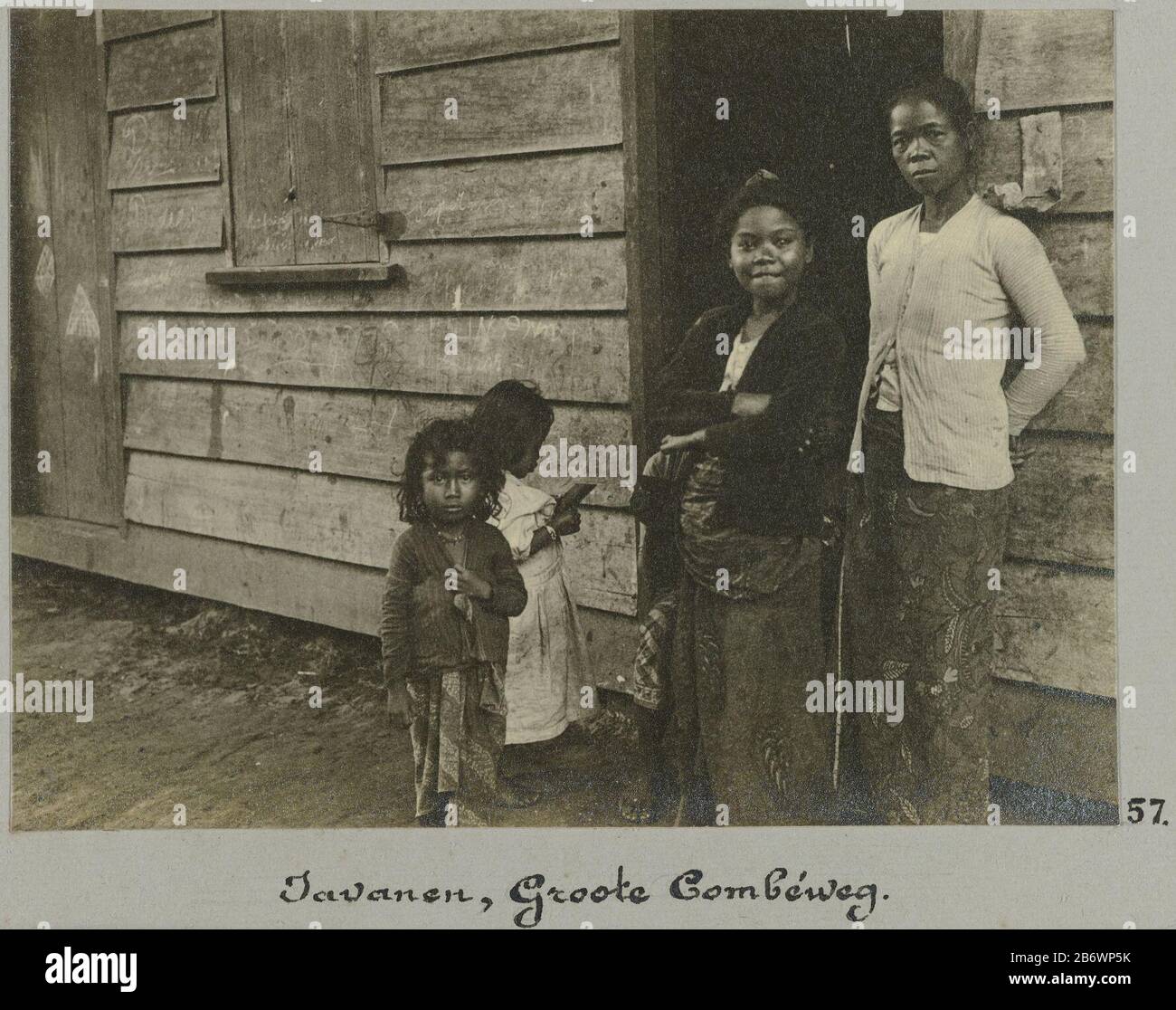 Two Javanese women and two girls standing in front of a wooden house on ...