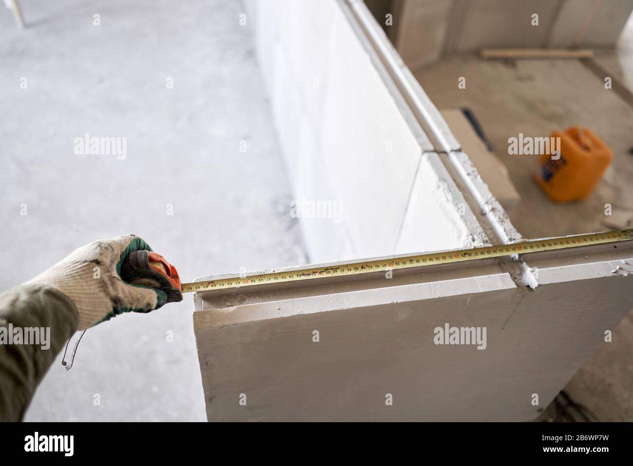 The construction worker measures with a tape measure Gypsum plate ...