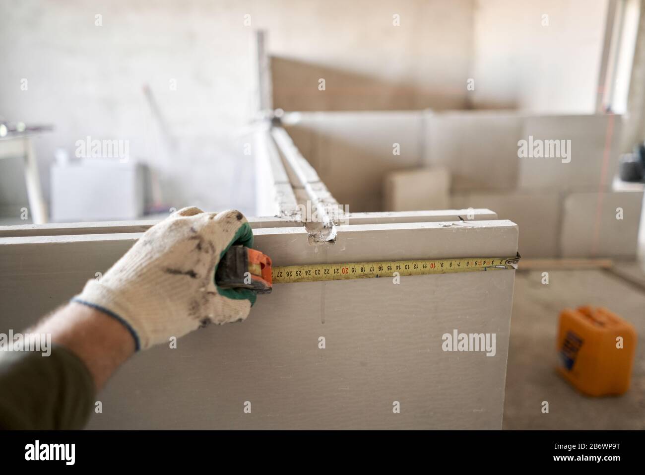 The construction worker measures with a tape measure Gypsum plate ...