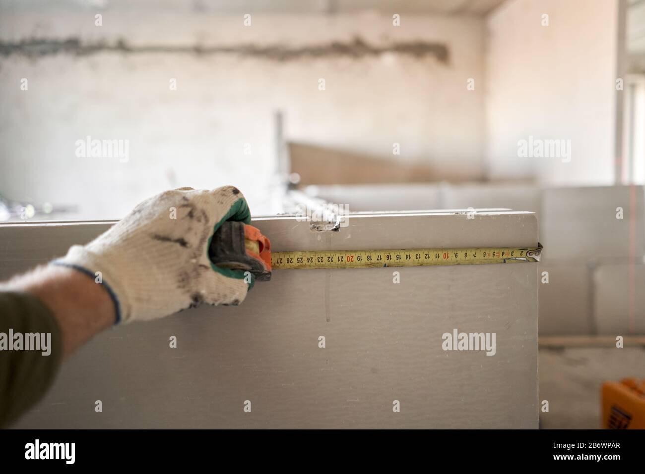 The construction worker measures with a tape measure Gypsum plate ...