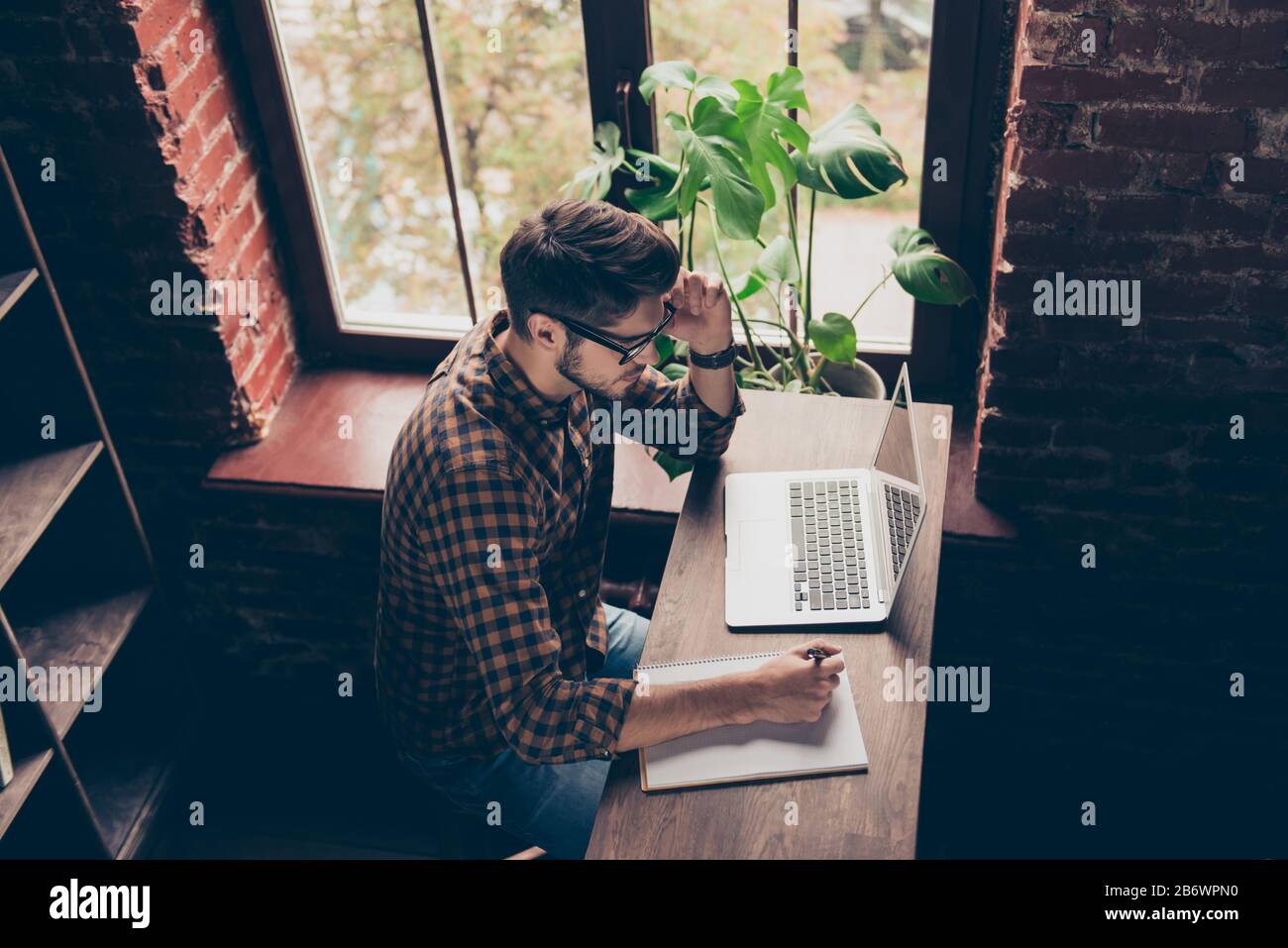 Top view of smart guy working on laptop and making notes Stock Photo ...