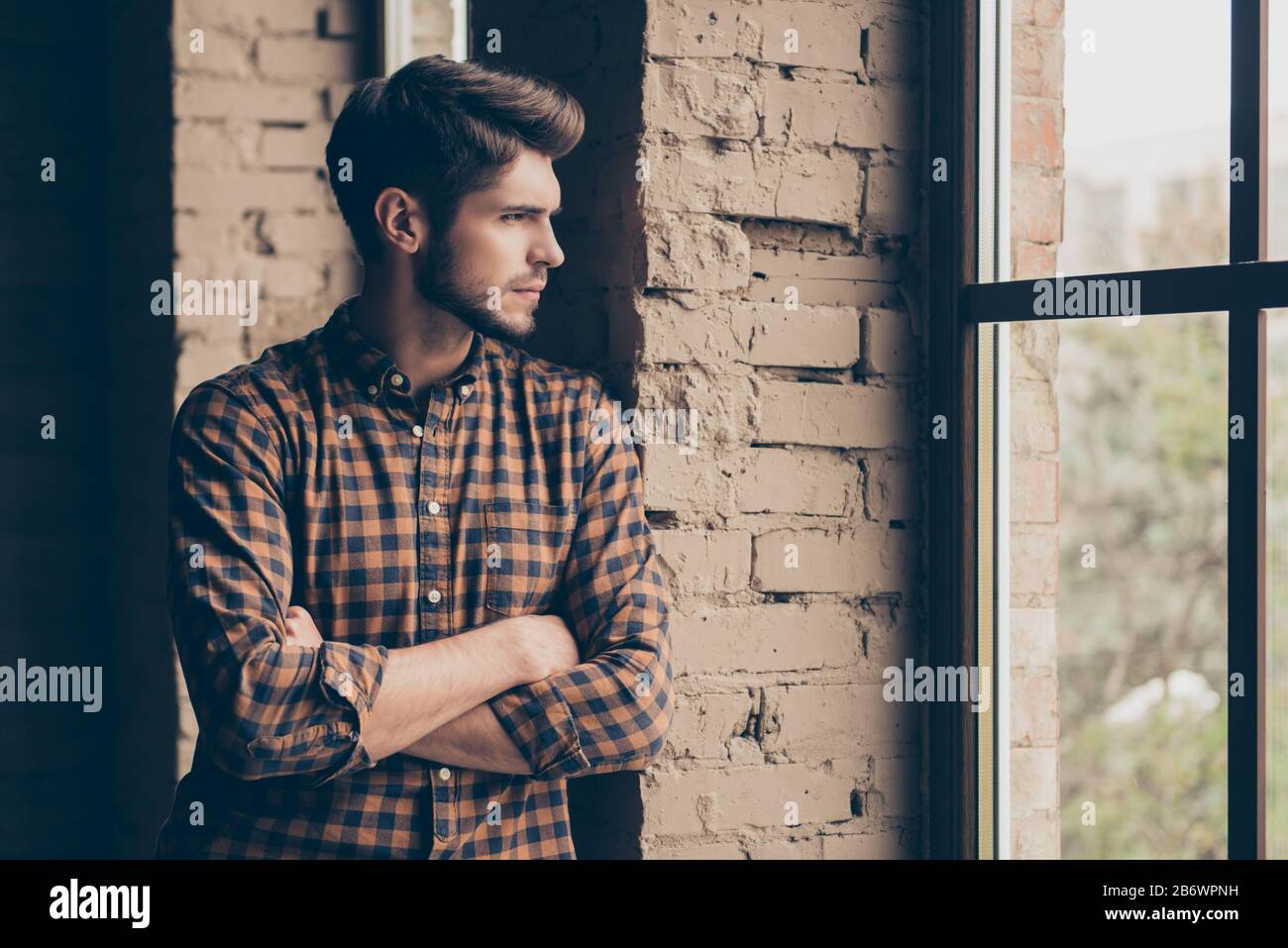 Portrait of young man with crossed hands looking in window Stock Photo ...
