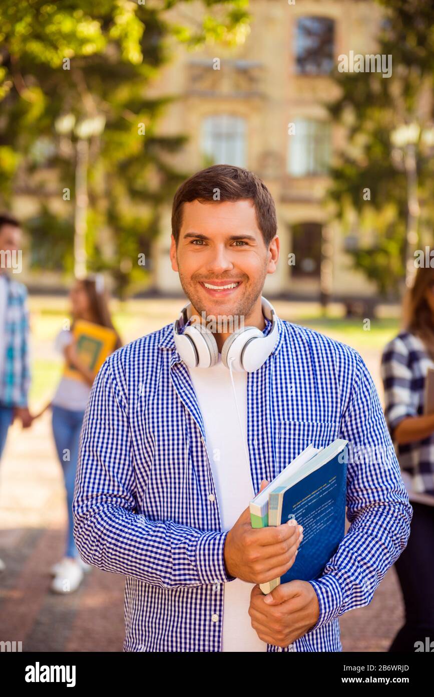 Young handsome smiling student with books standing near university ...