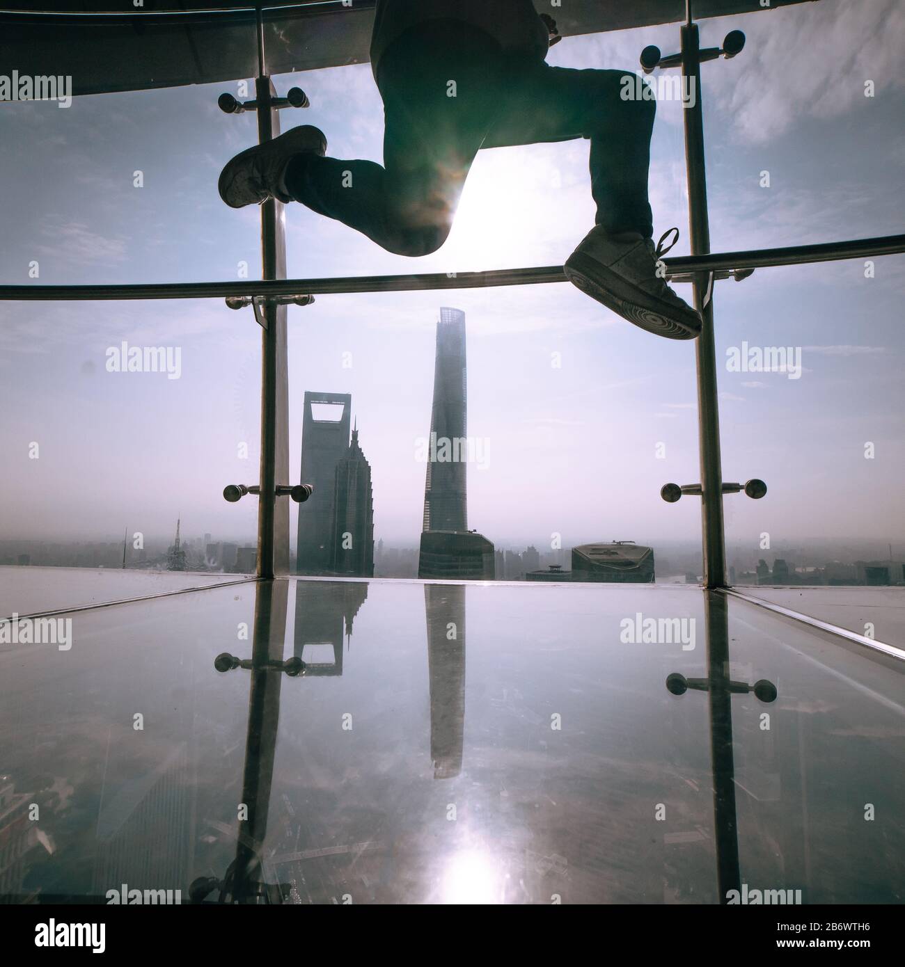 Male jumping inside of building with glass floor and view of skyline of ...