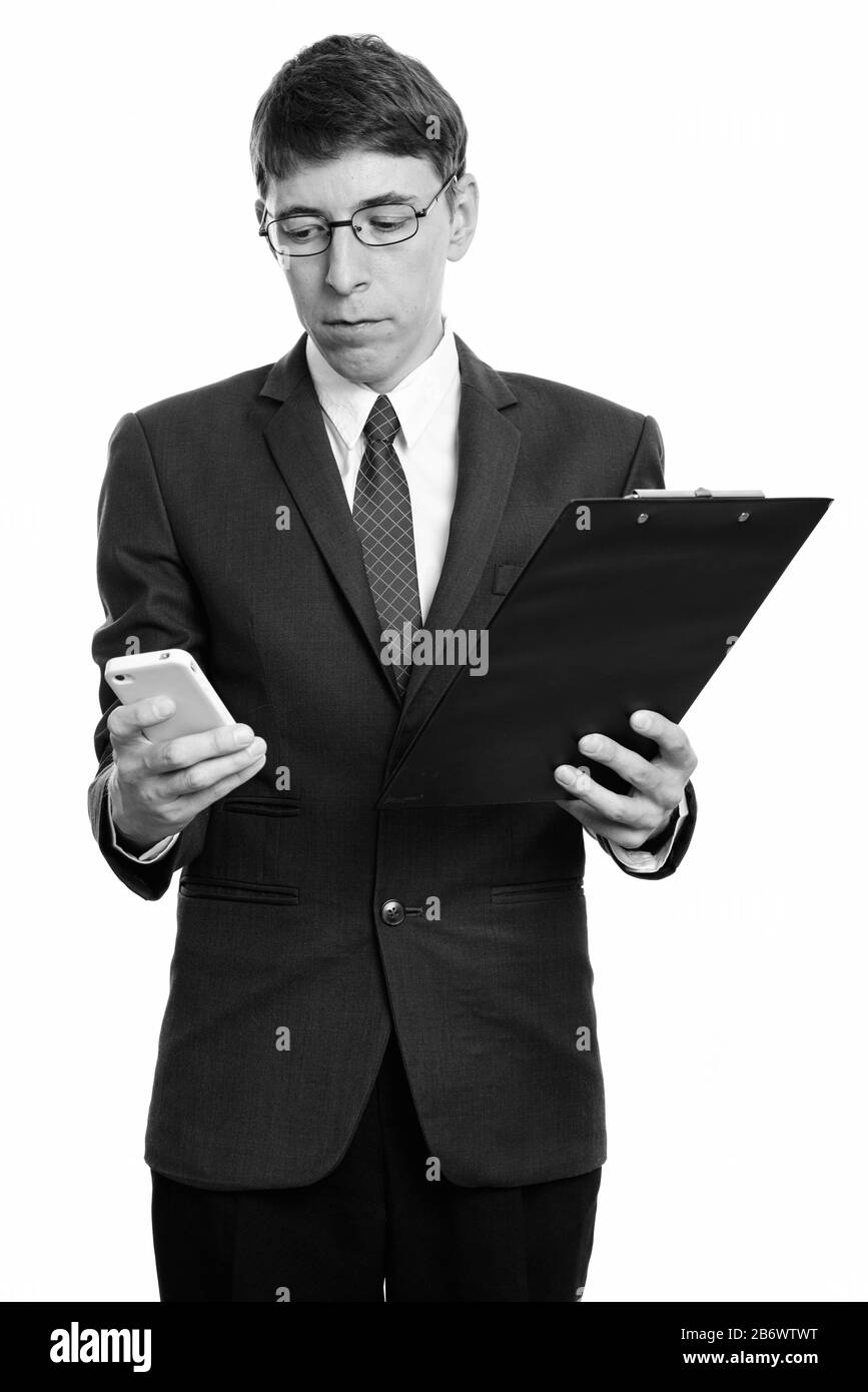 Studio shot of businessman holding clipboard while using mobile phone ...