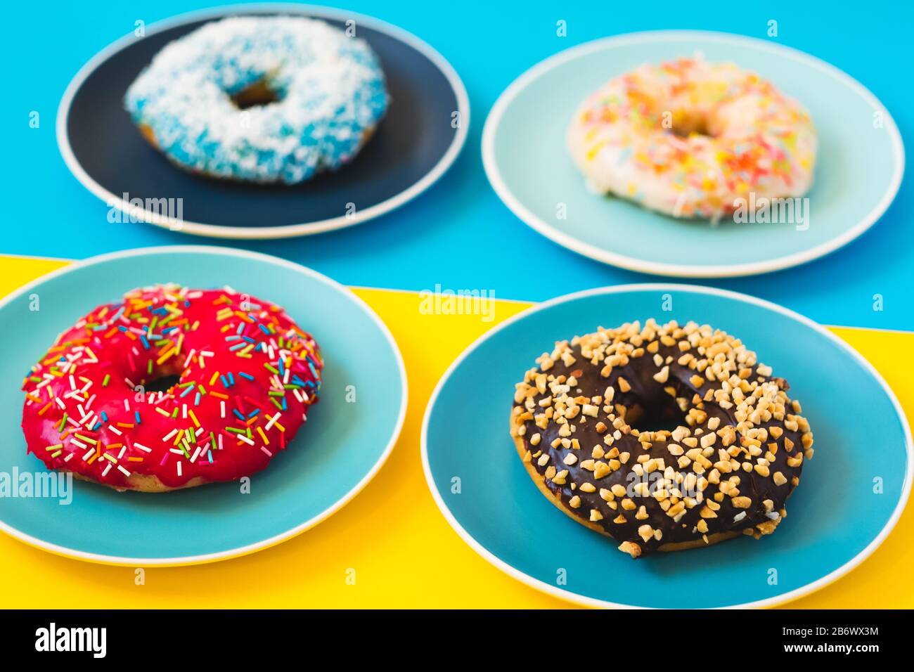 Fresh appetizing 4 donuts lying on plate in colored yellow and blue ...
