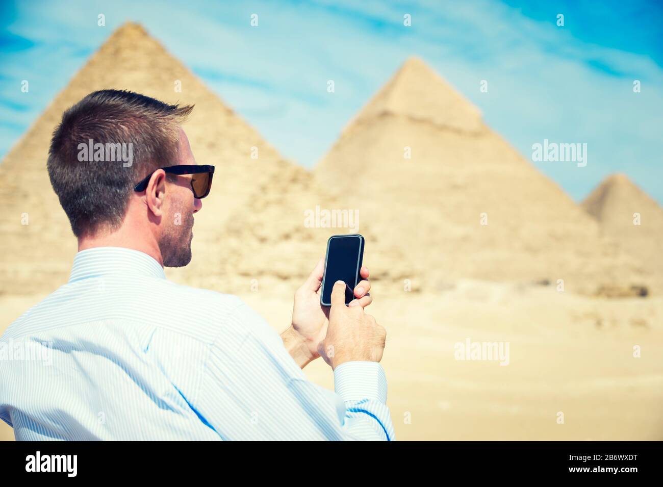 Businessman using his smartphone in desert sun against background of ...