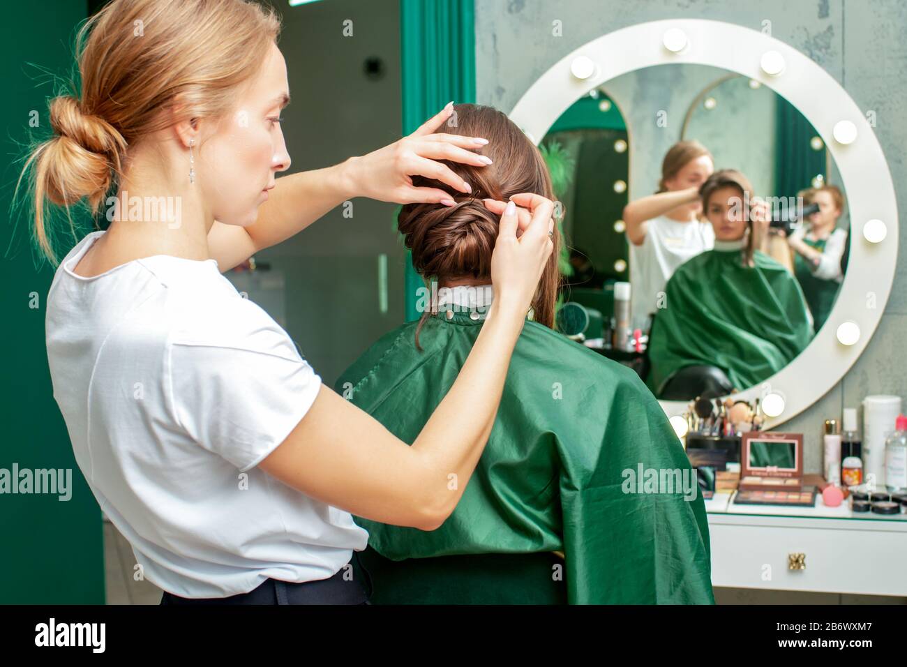 Professional hairdresser making hairstyle for woman in beauty salon ...