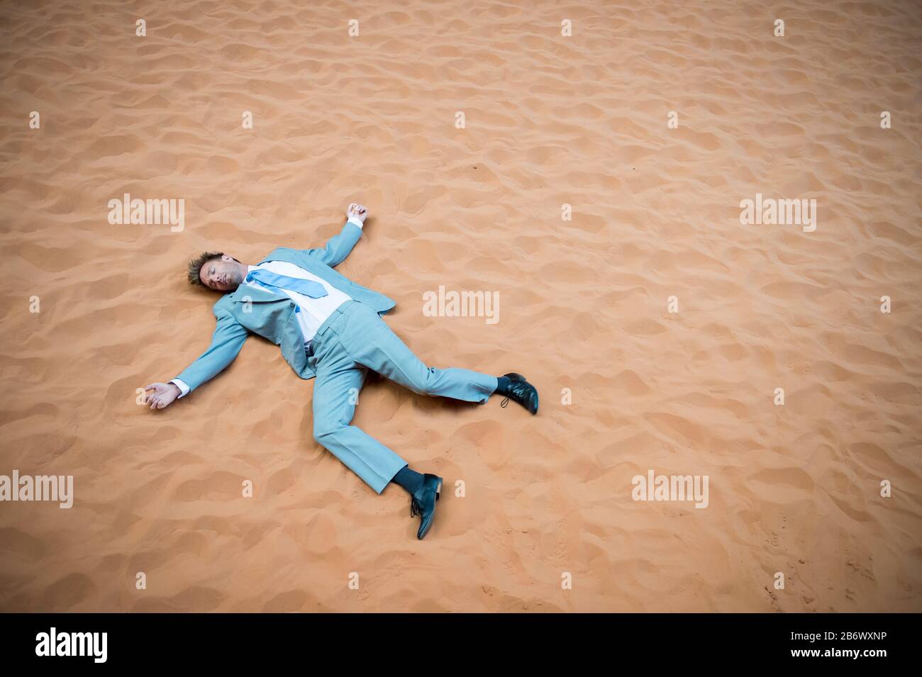 Unconscious businessman lying down collapsed on red sand desert ...