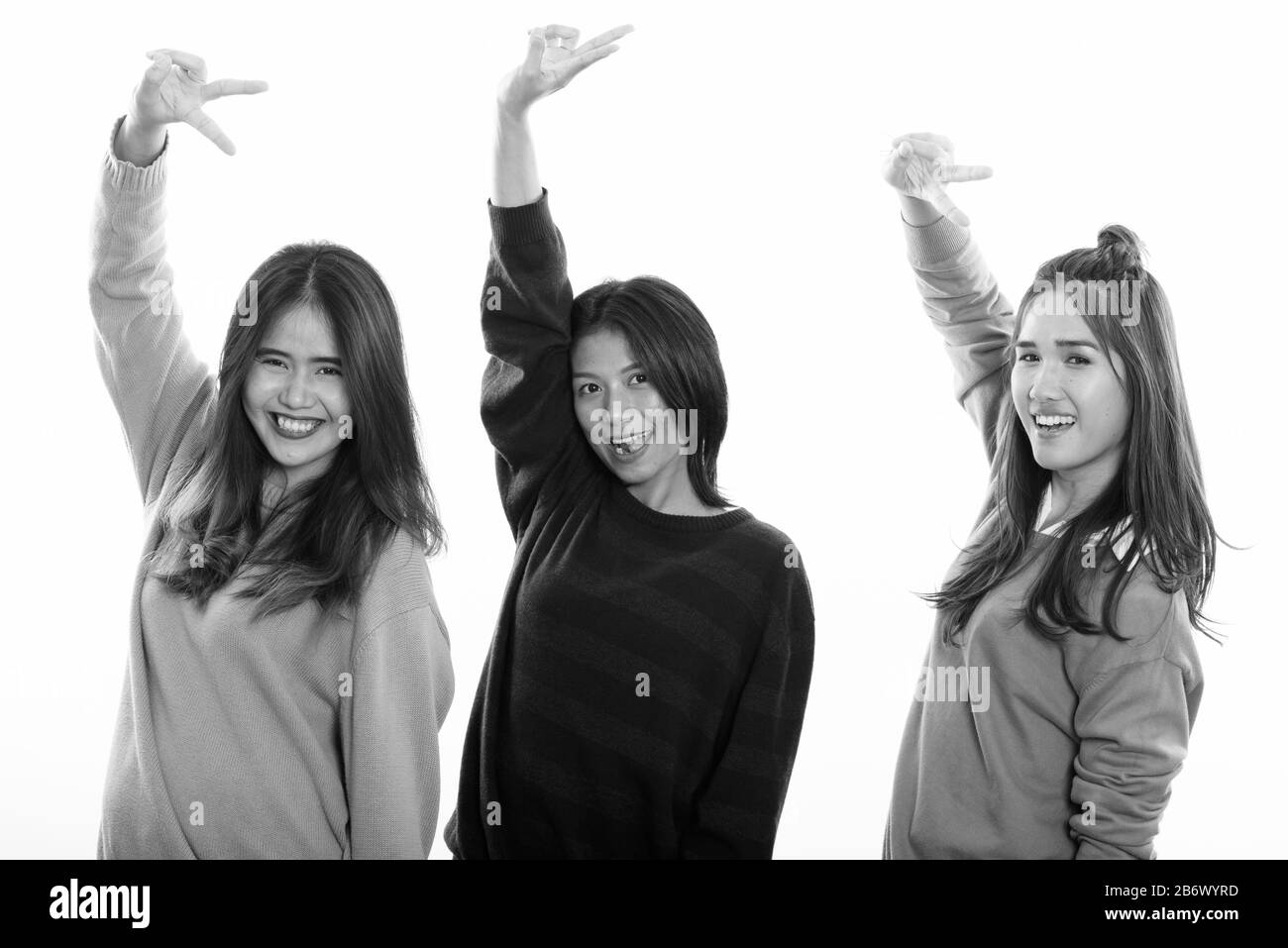 Studio shot of three happy young Asian woman friends smiling while ...