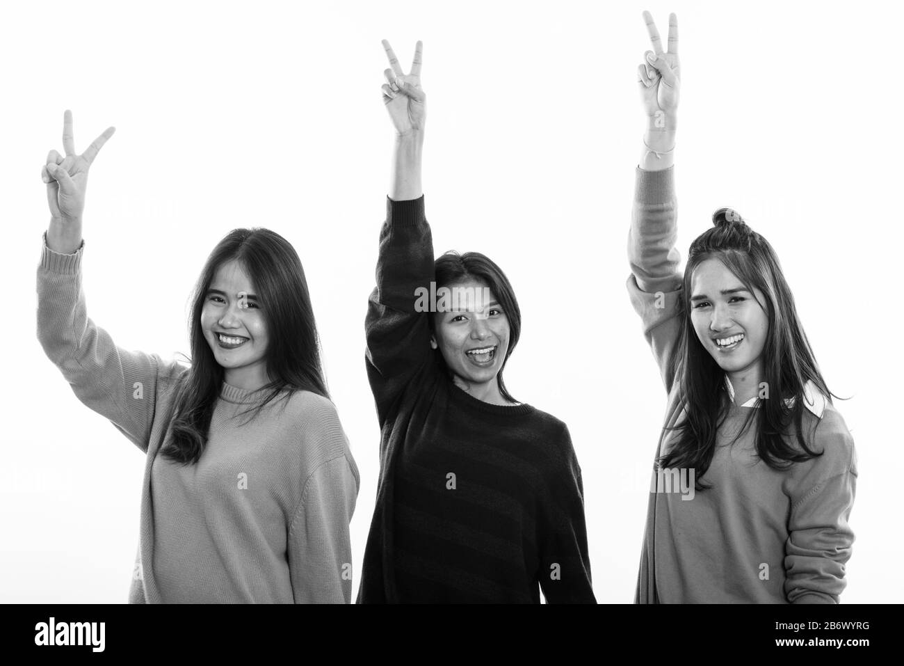 Studio shot of three happy young Asian woman friends smiling while ...